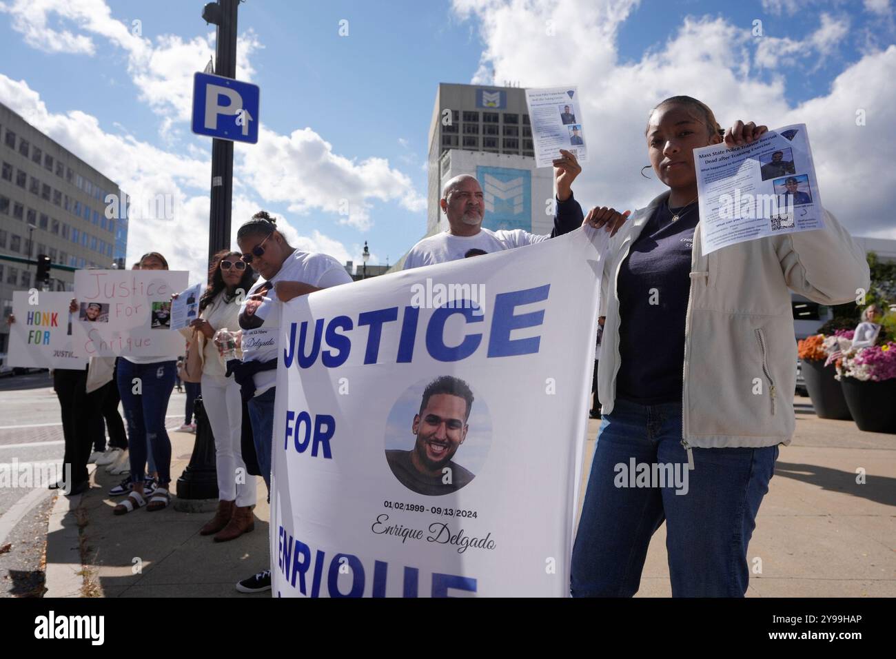People display signs with with a likeness of Massachusetts State Police recruit Enrique Delgado ...