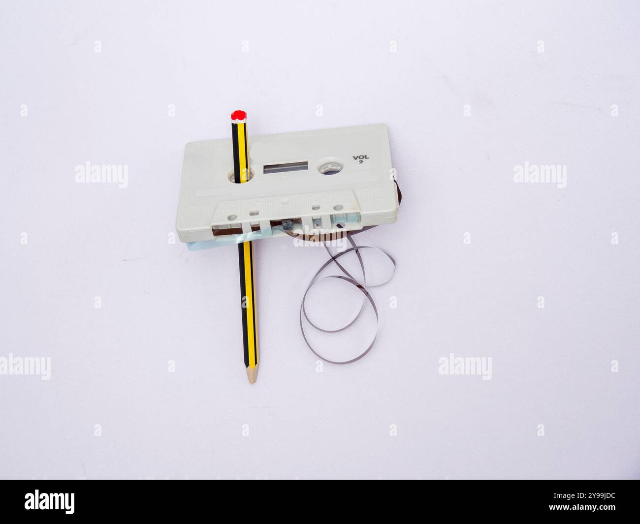 Plastic retro cassette with loose magnetic tape being wound by a pencil ...