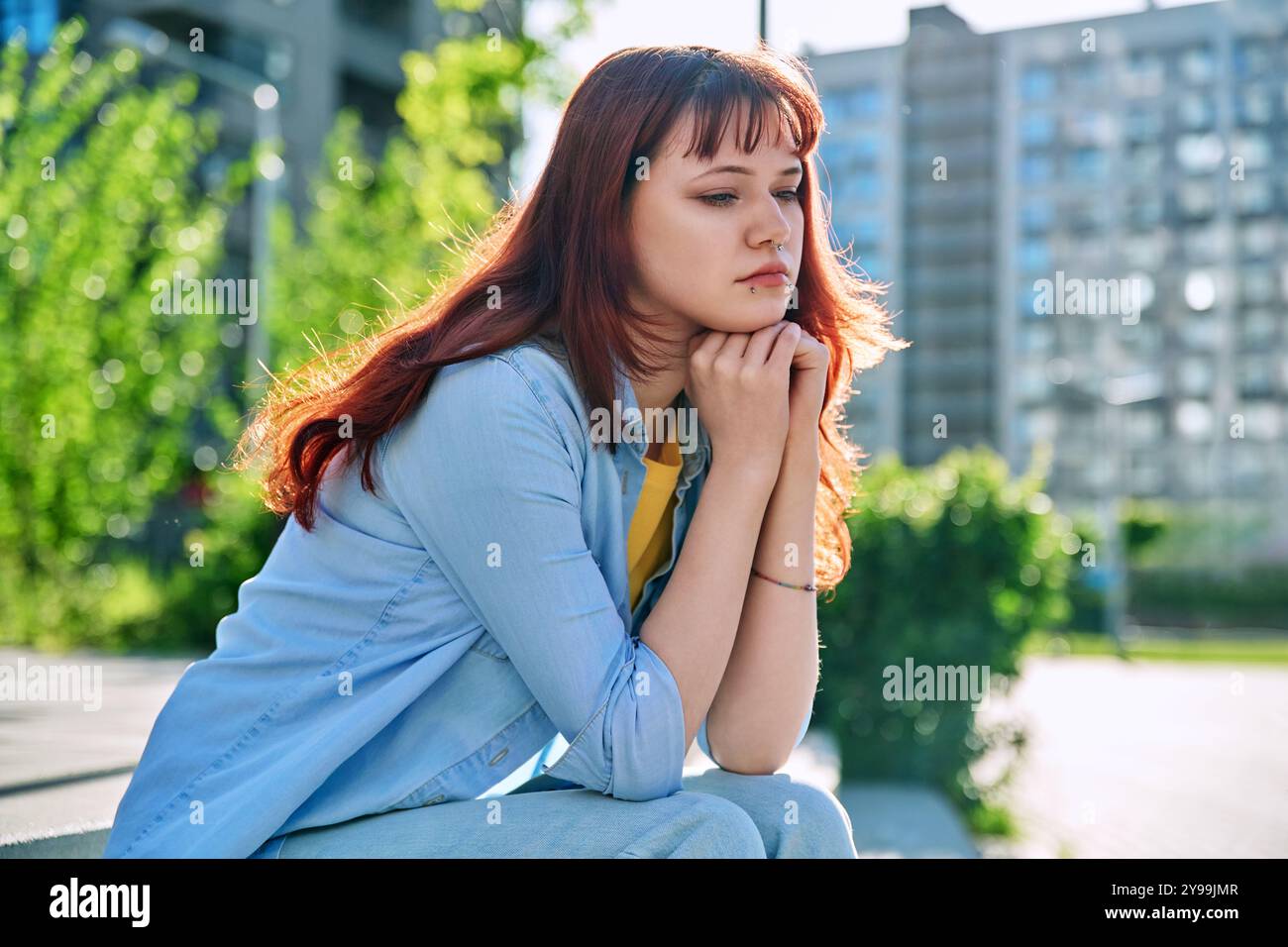 Upset sad unhappy young female sitting outdoor Stock Photo - Alamy