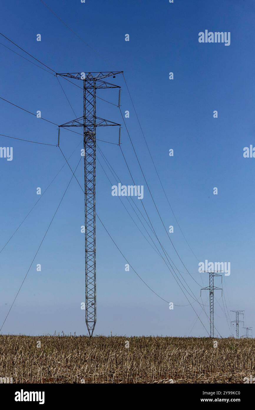 High voltage power transmission towers, with a cloudless blue sky and the base being a ...