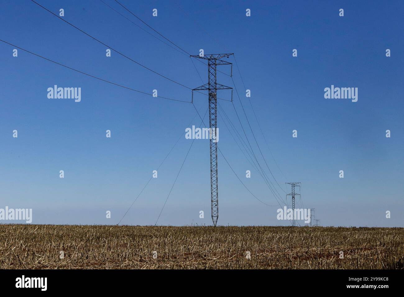 High voltage power transmission towers, with a cloudless blue sky and ...
