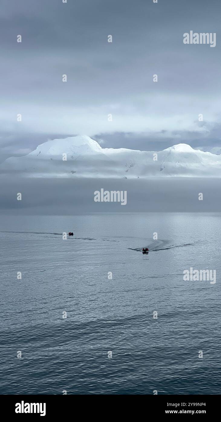 Two small expedition boats head toward the snow-covered mountains of ...