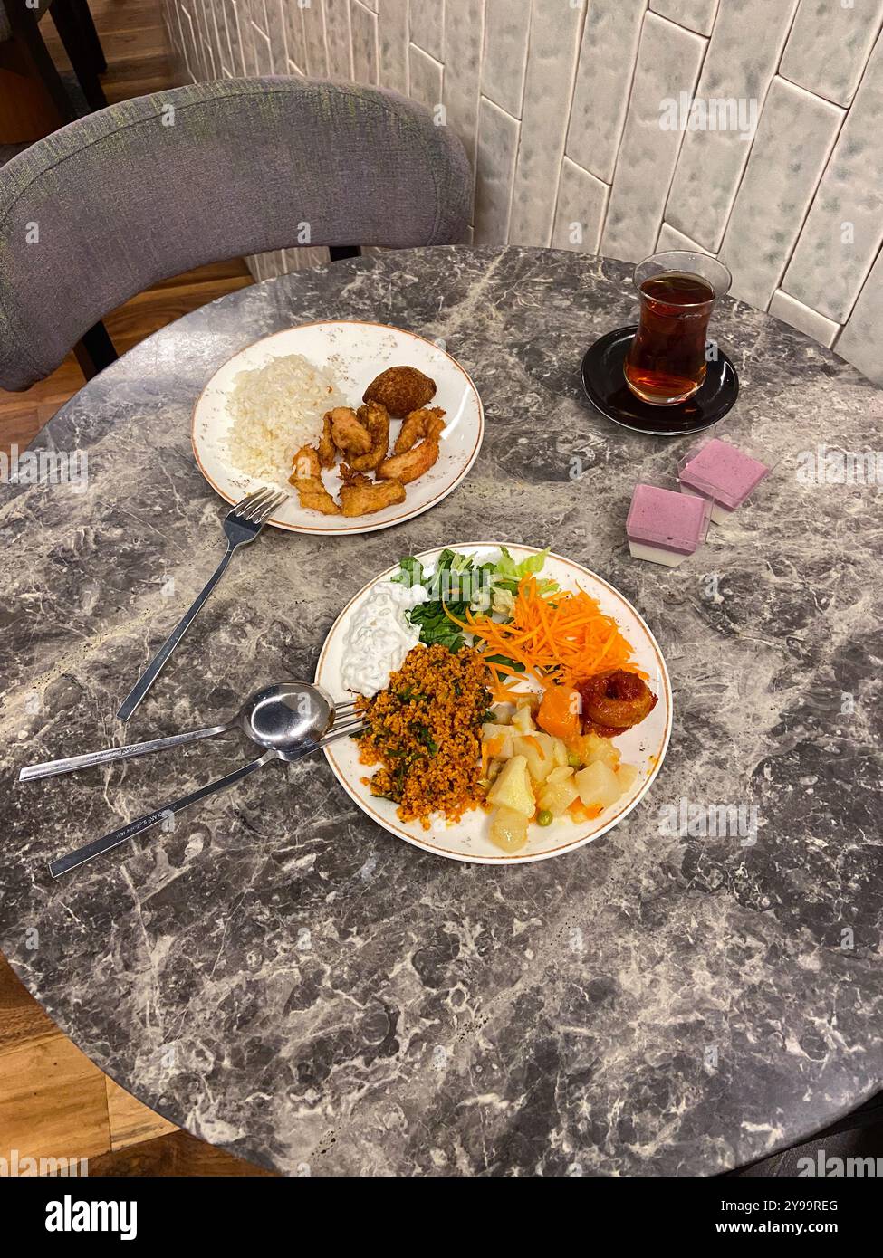 Two plates of diverse cuisine on a marble table, showcasing a ...