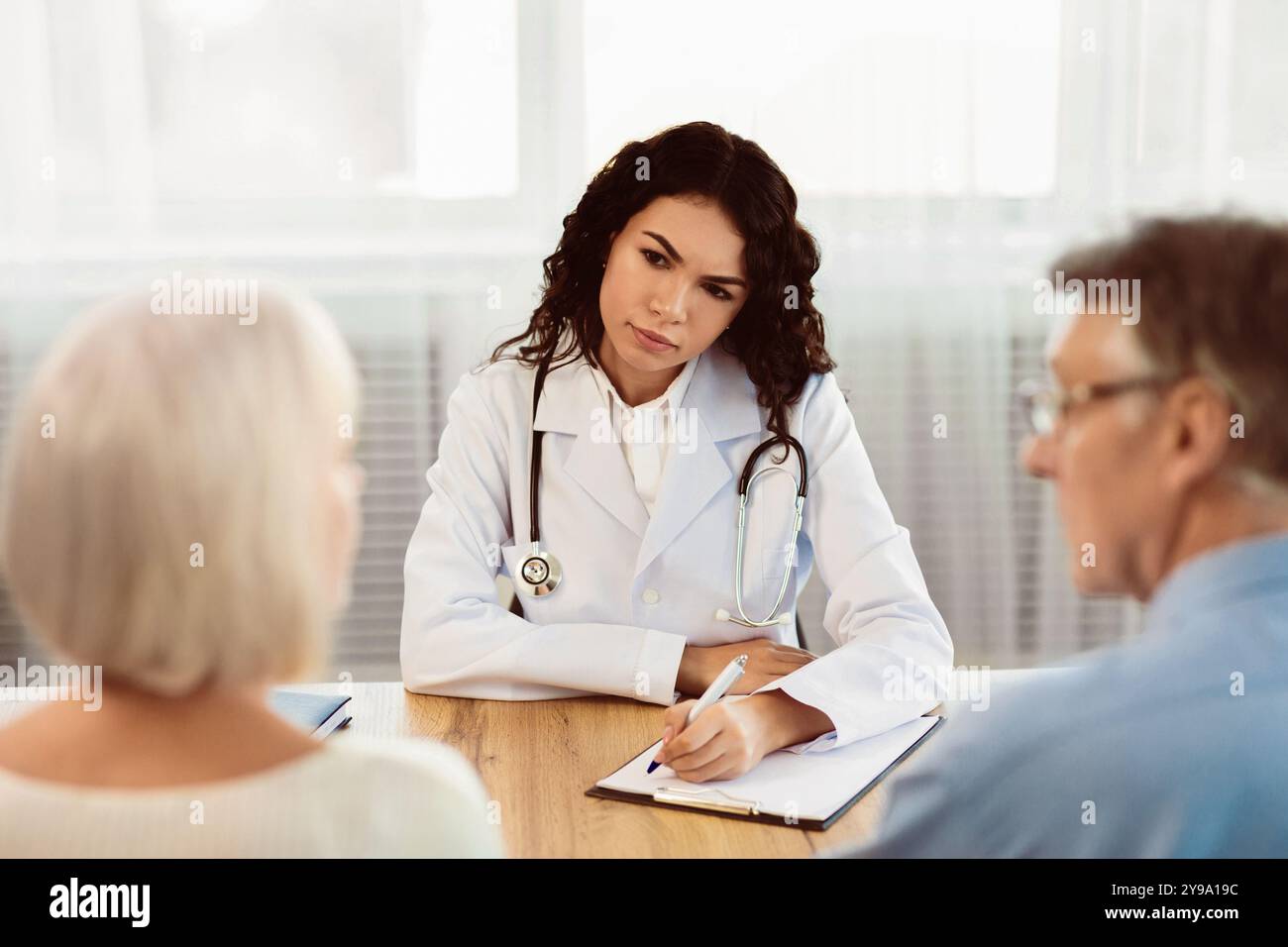 Brazilian doctor writing diagnosis consulting mature couple Stock Photo ...