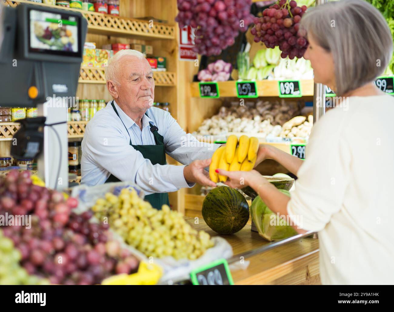 Male grocery store worker handing bananas to customer after payment at ...