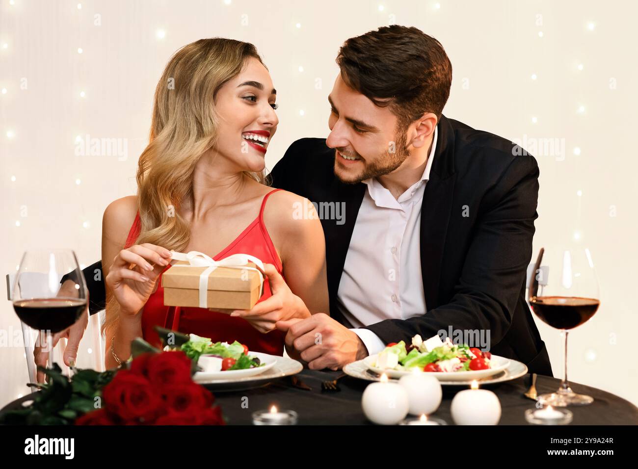 Loving man giving surprise gift to girlfriend on date in restaurant ...