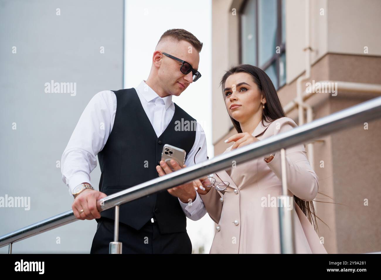 Elegantly Dressed Couple Engaged in Conversation on a Modern Staircase ...