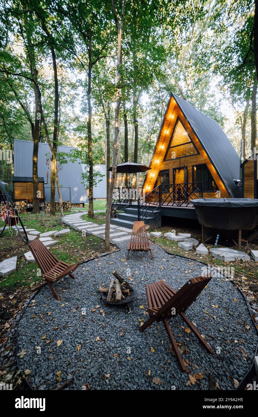 Modern A-frame cabin with illuminated exterior, surrounded by trees and ...