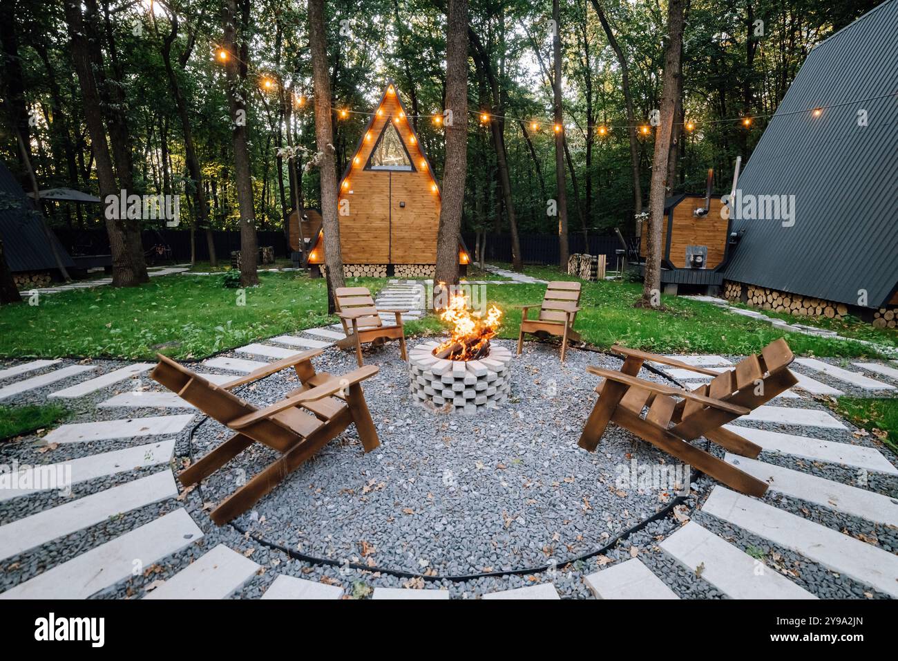 Campfire area with wooden chairs and cabins in background, creating a ...