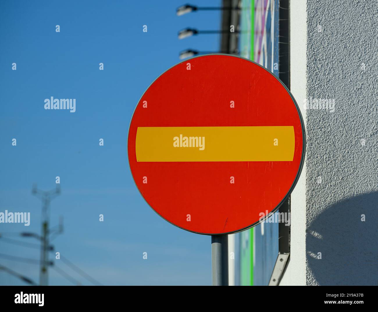 A bright red no entry sign with a horizontal yellow bar is mounted on a ...