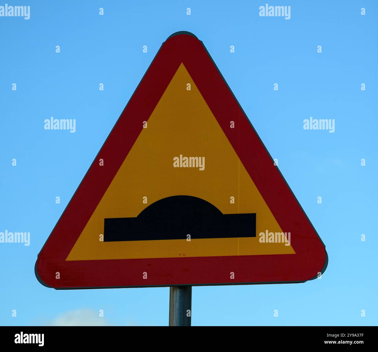 A triangular warning sign alerts drivers about an uneven road surface ...