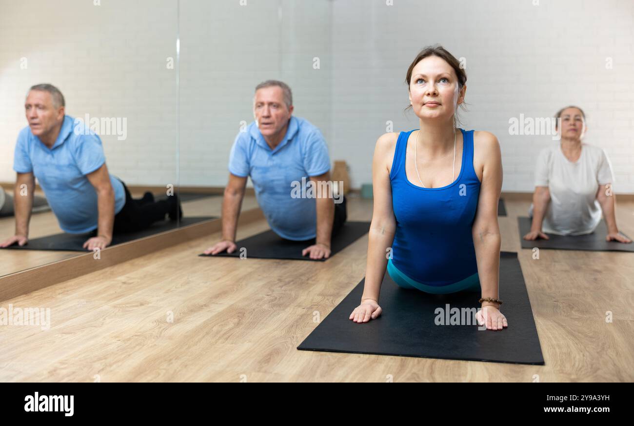 People of different ages performing cobra exercise during group Pilates ...