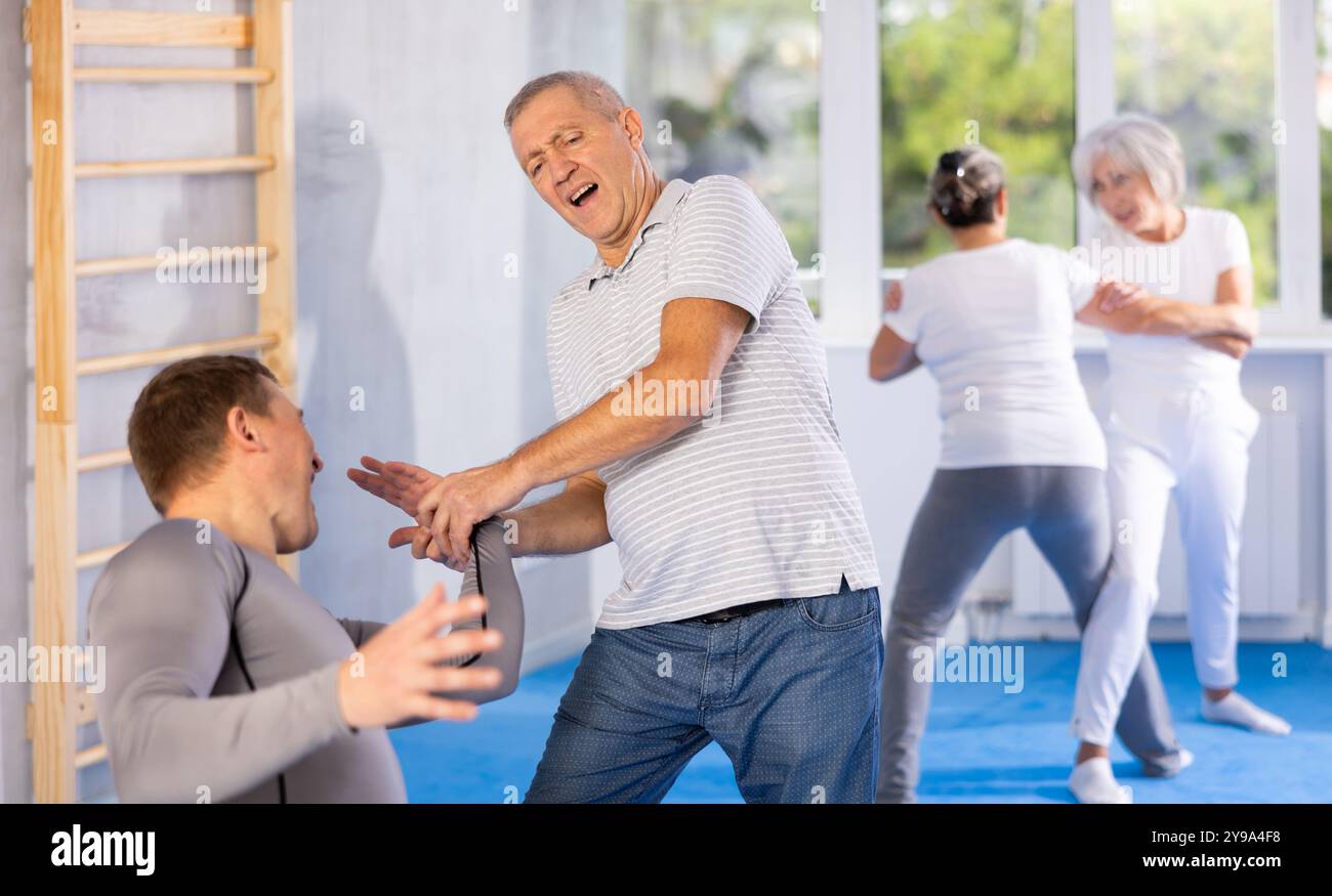 Old man twisting her opponent's arm during self-defense classes Stock ...
