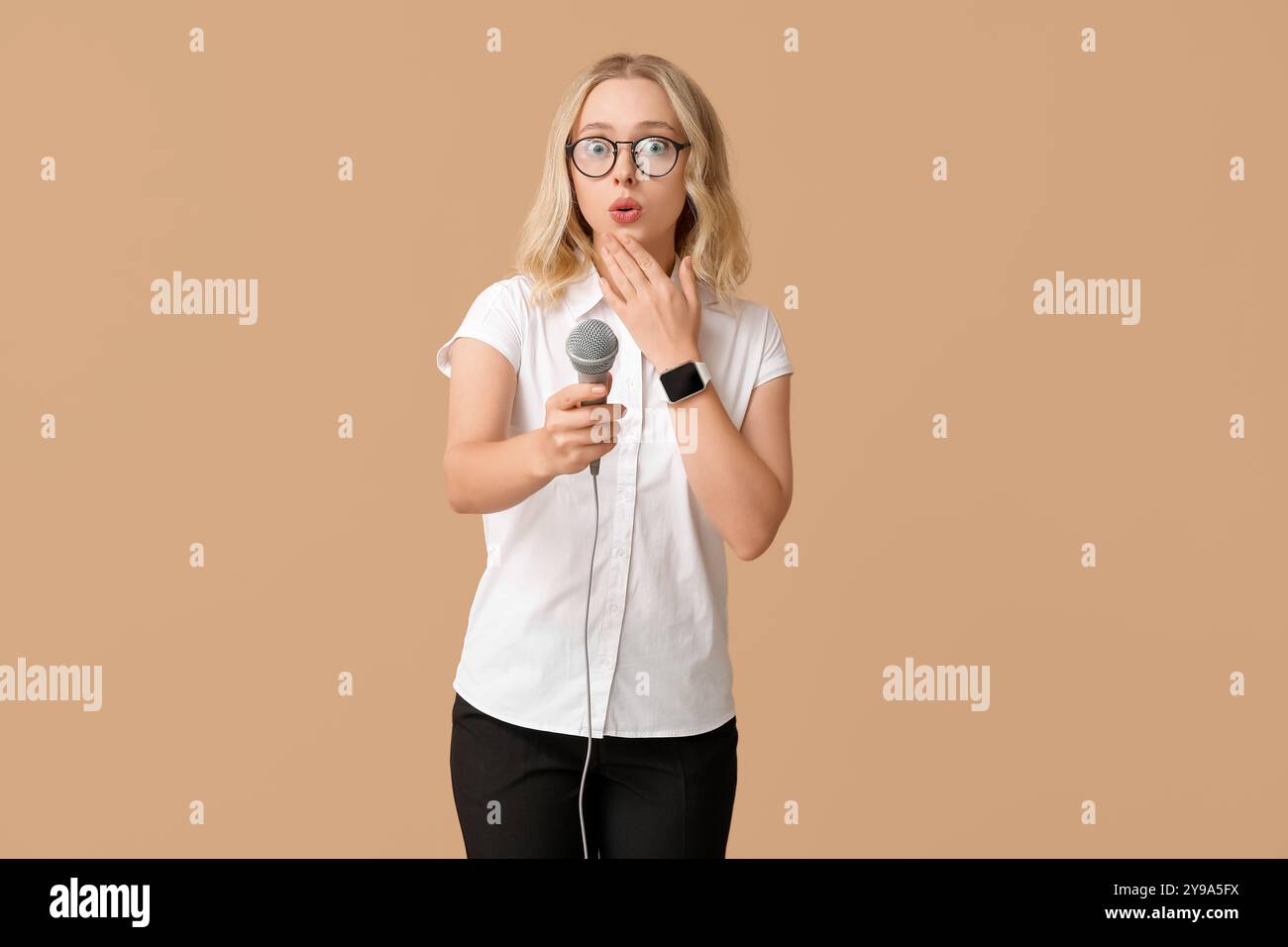 Portrait of shocked female journalist with microphone taking interview ...