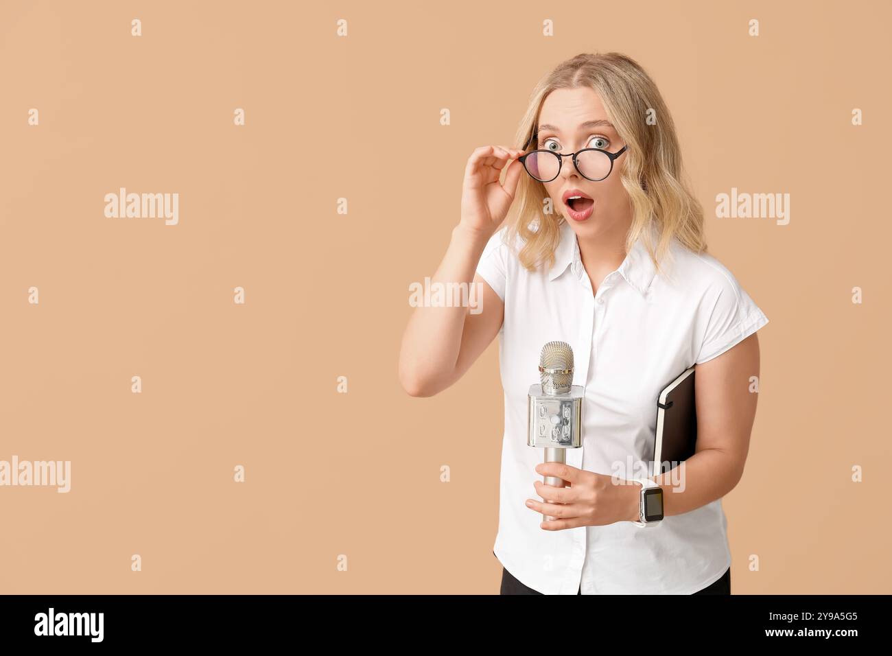 Portrait of shocked female journalist with microphone taking interview ...