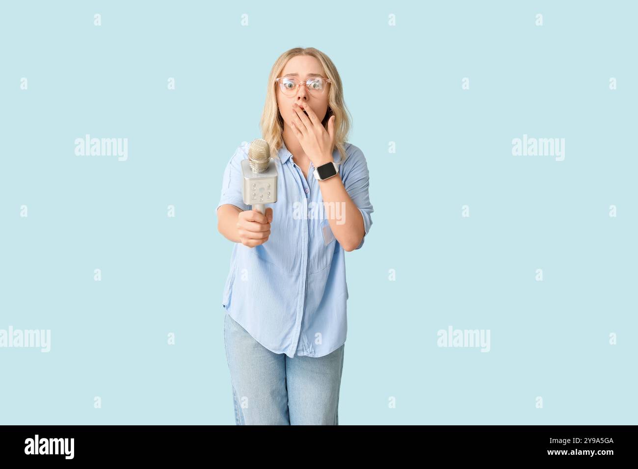 Portrait of shocked female journalist with microphone taking interview ...