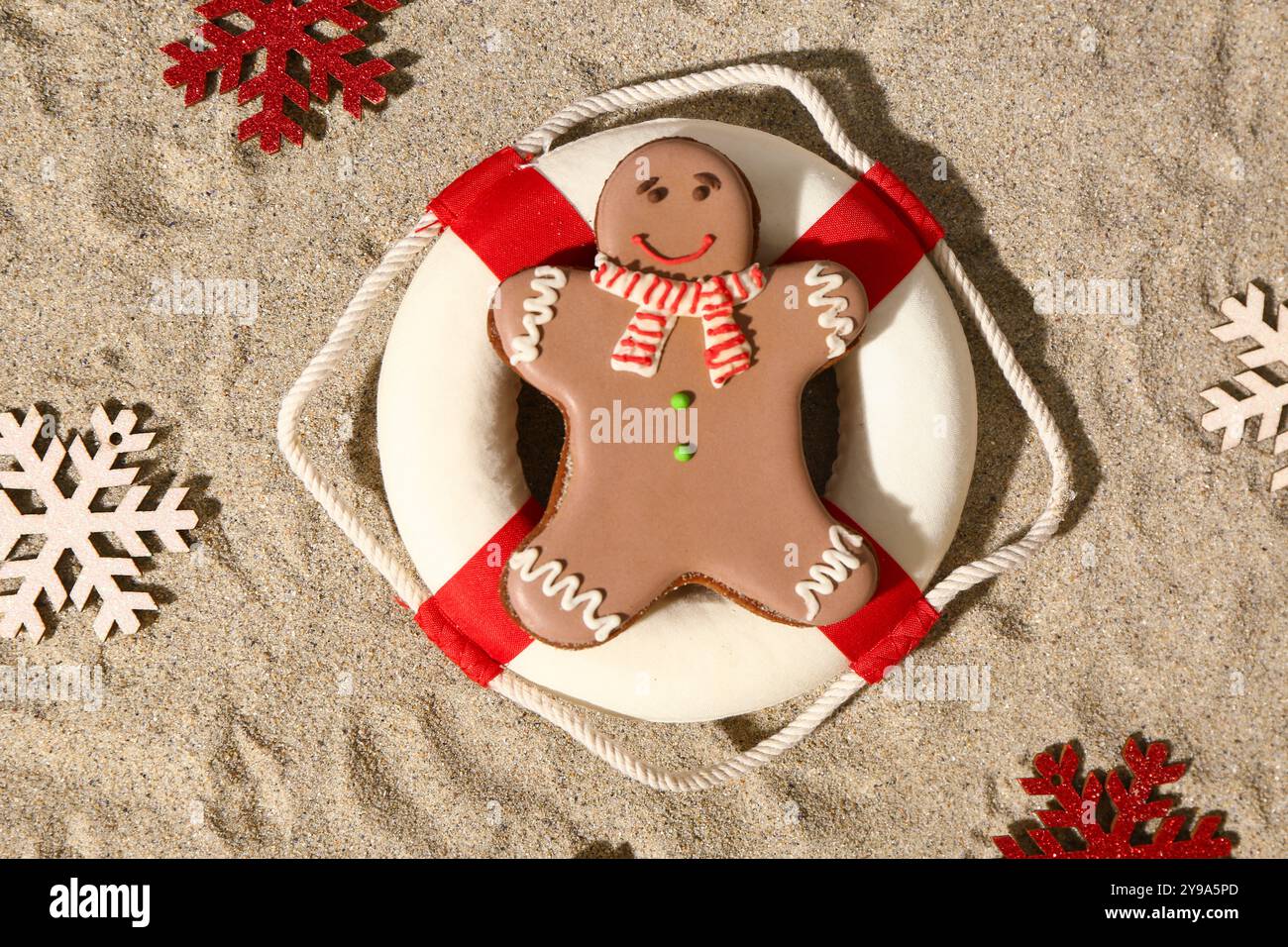 Gingerbread cookie with mini lifebuoy and Christmas decorations on sand ...