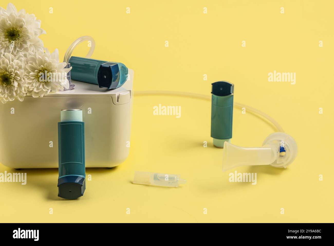 Modern nebulizer with inhalers and chrysanthemum flowers on yellow ...