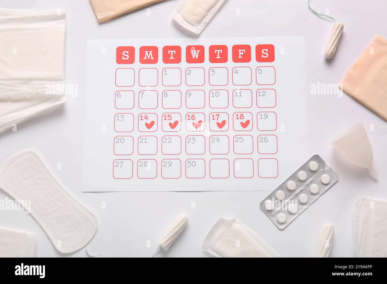 Menstrual calendar with pads, tampons, cup and pills on white ...