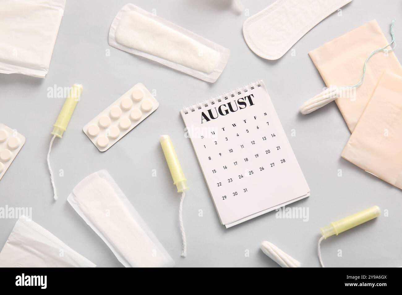 Menstrual calendar with pads, tampons and pills on grey background ...