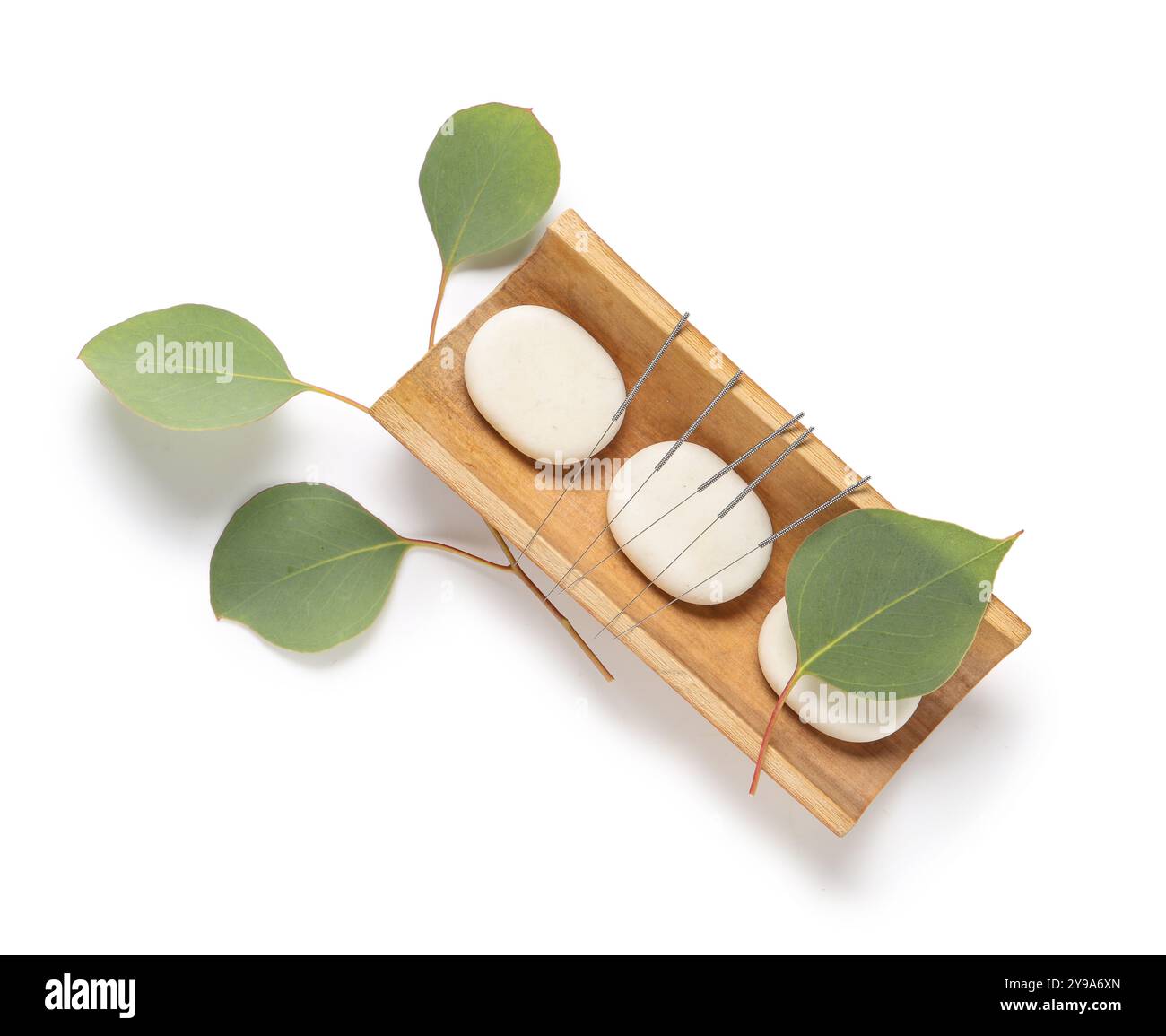 Bamboo stand with acupuncture needles and spa stones on white ...