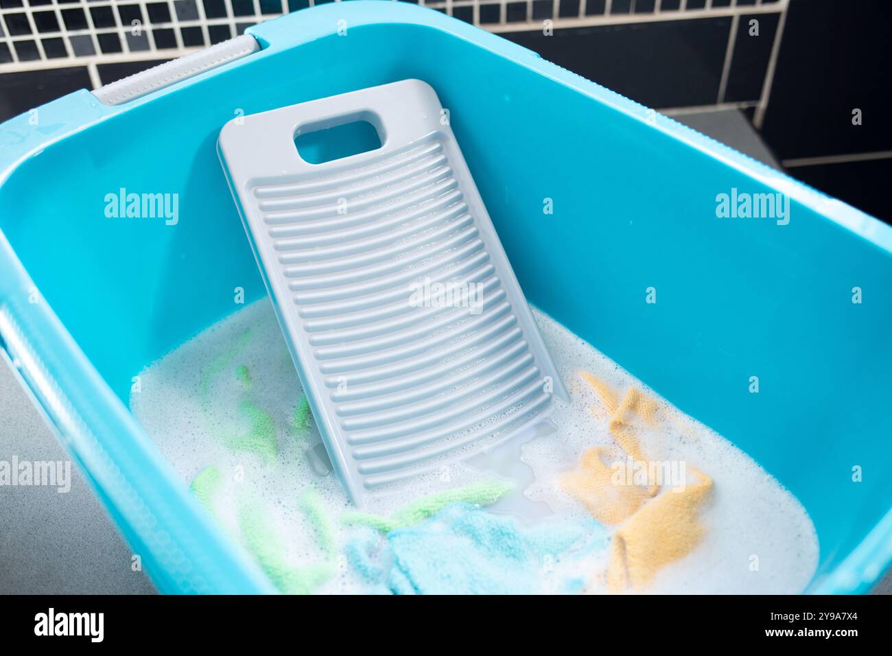 Washboard in blue basin, soapy water, yellow sponge, traditional ...