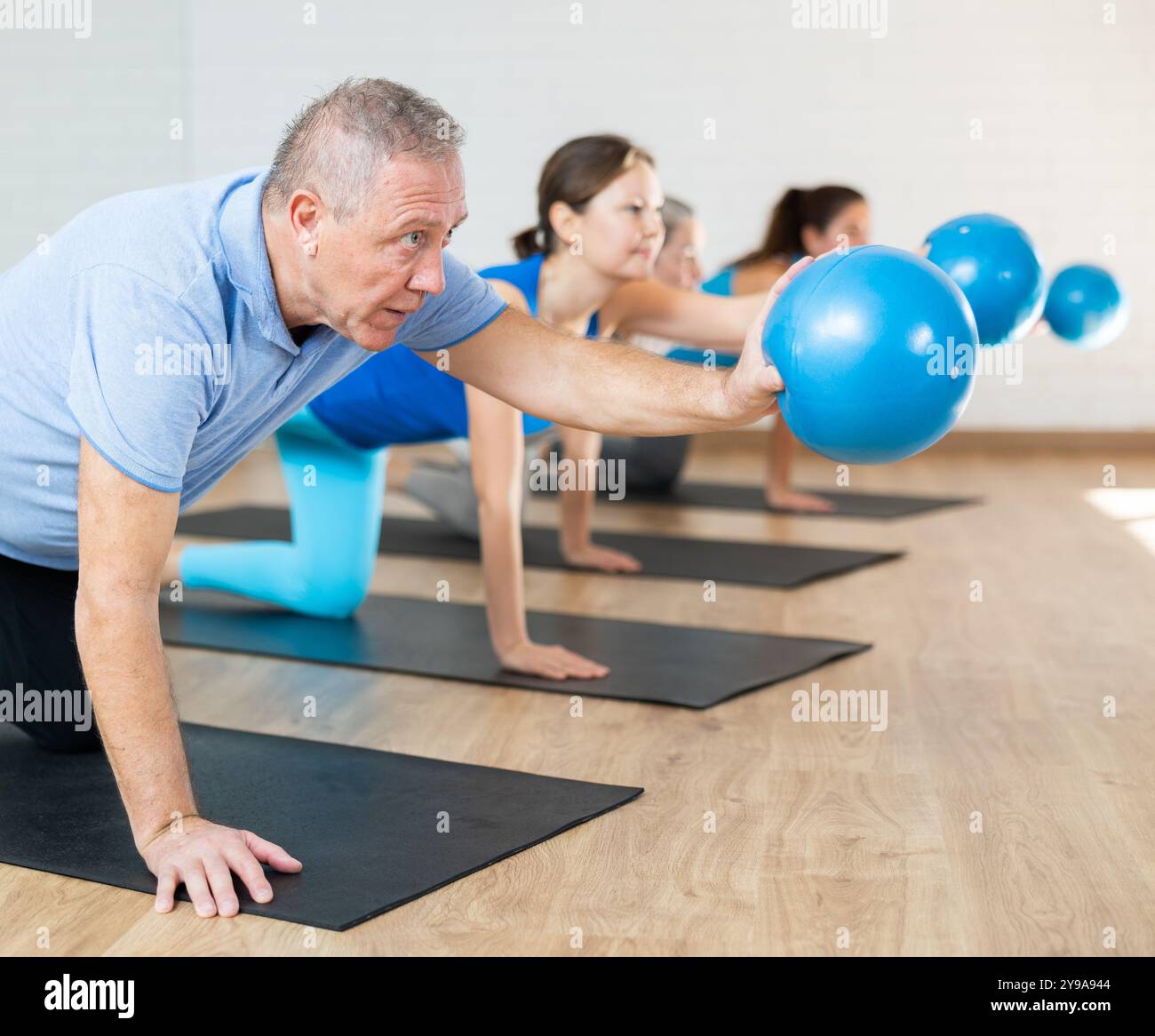 People of different ages stretching leg and arm, holding mini ball in ...