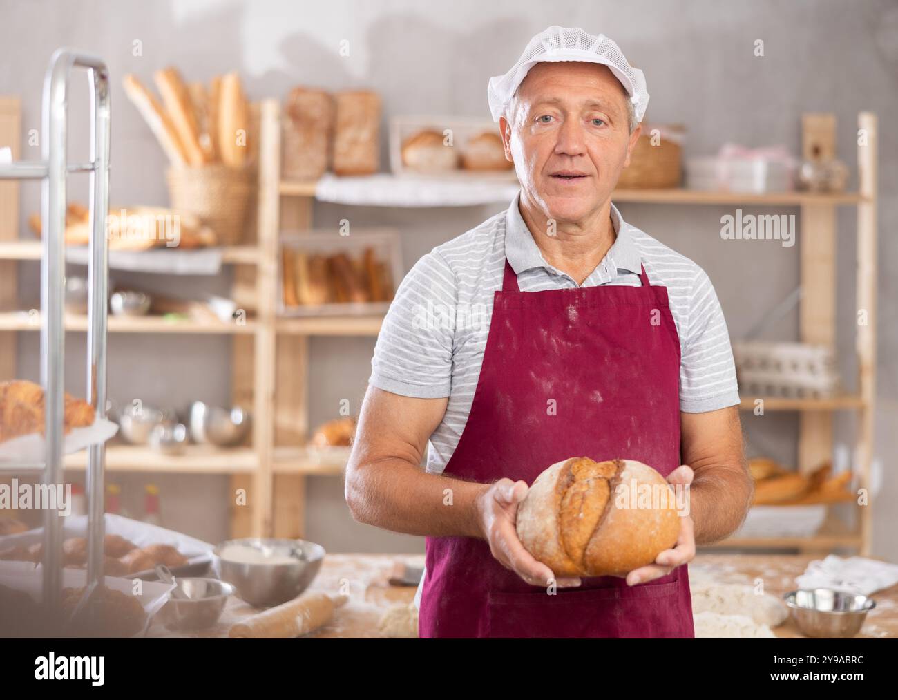 Bakery mature man employee holds ready-made loafs of bread Stock Photo ...
