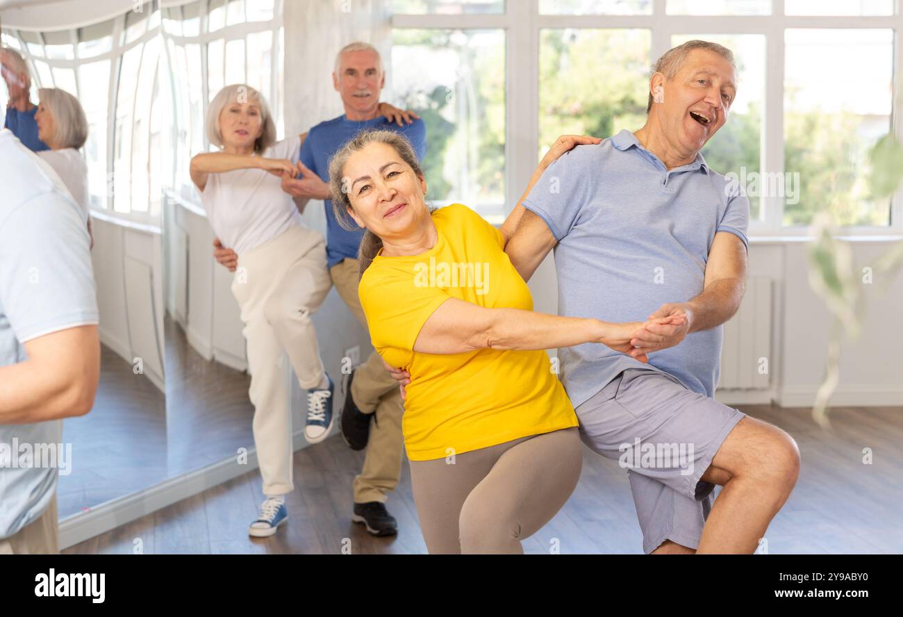 Group of mature men and woman in sportswear learning to dance latin ...