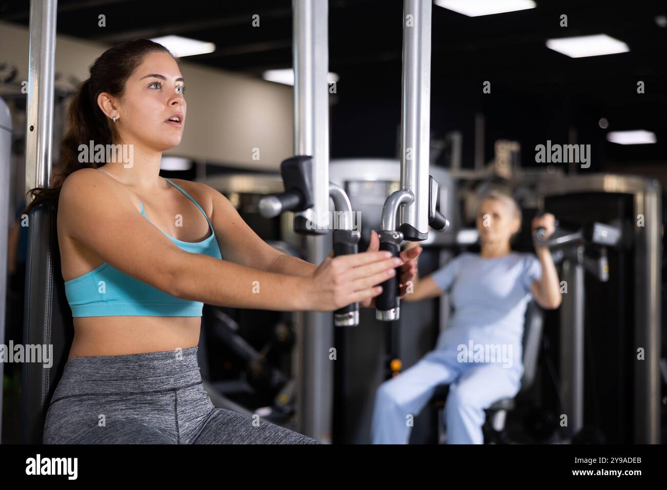 Girl performing butterfly exercise for chest in pec deck machine Stock ...