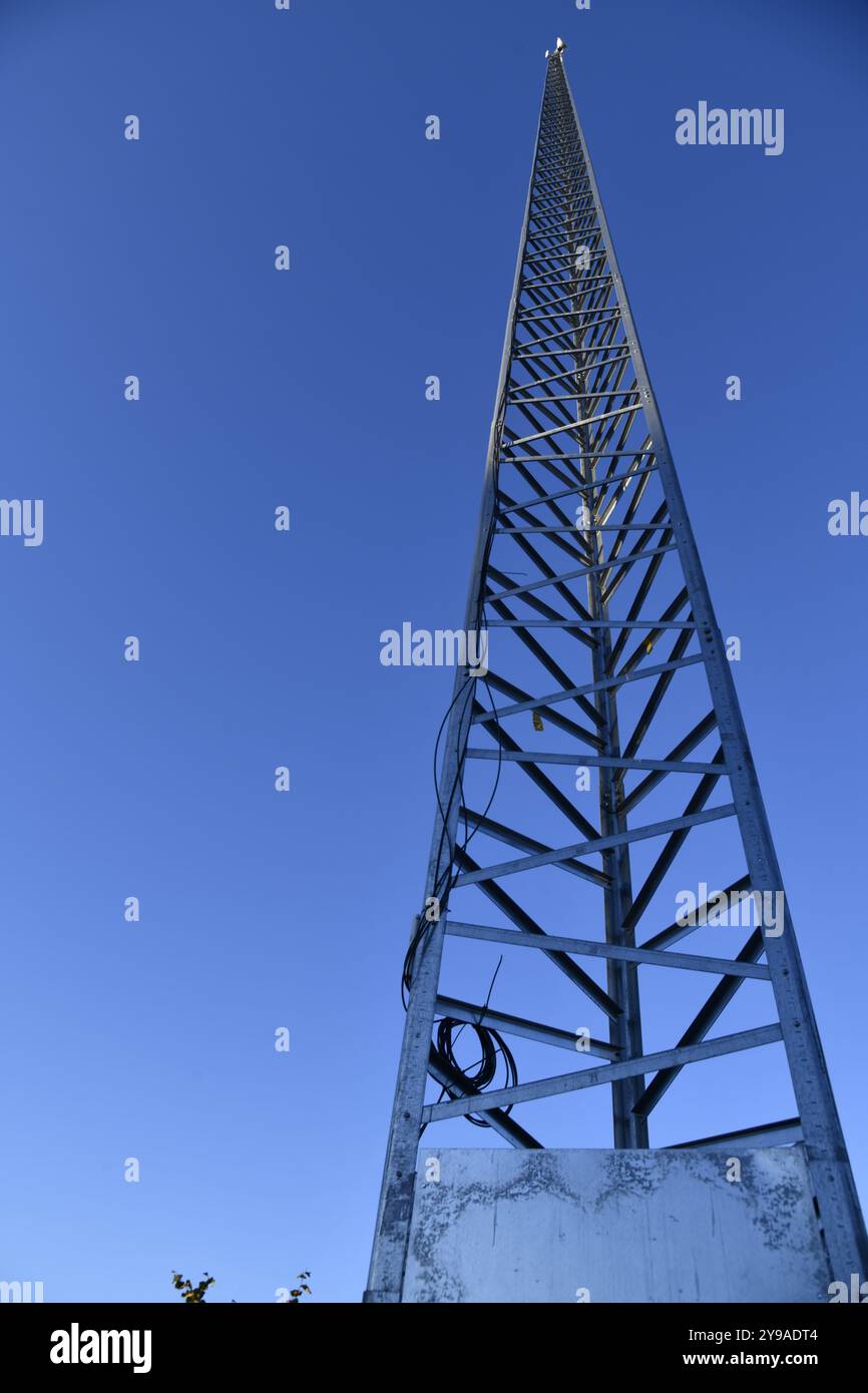 Communication tower rising up high in blue sky forming geometric design ...