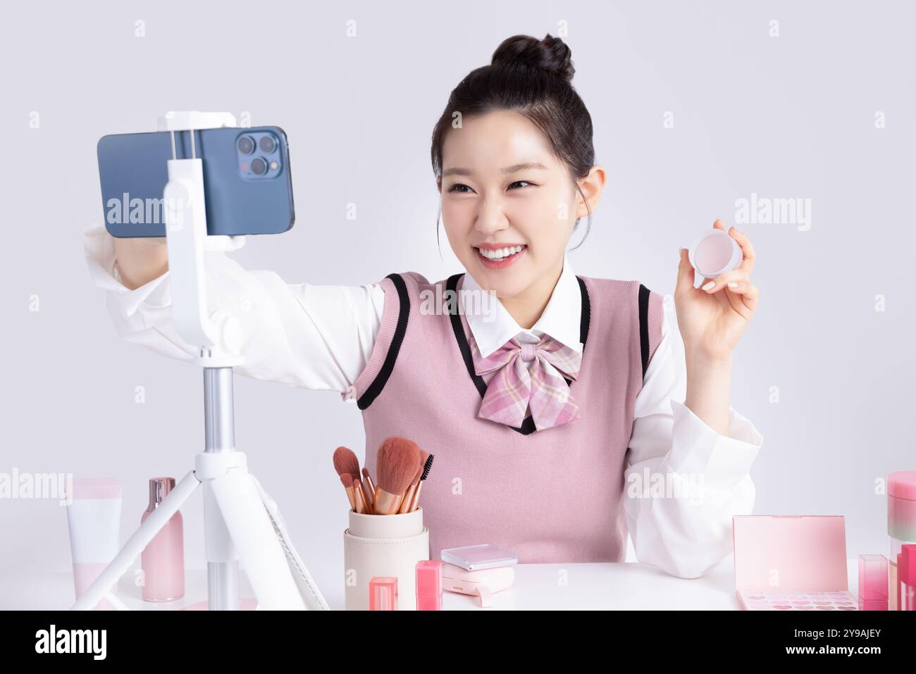 A teenage woman in school uniform laying out various cosmetics and ...