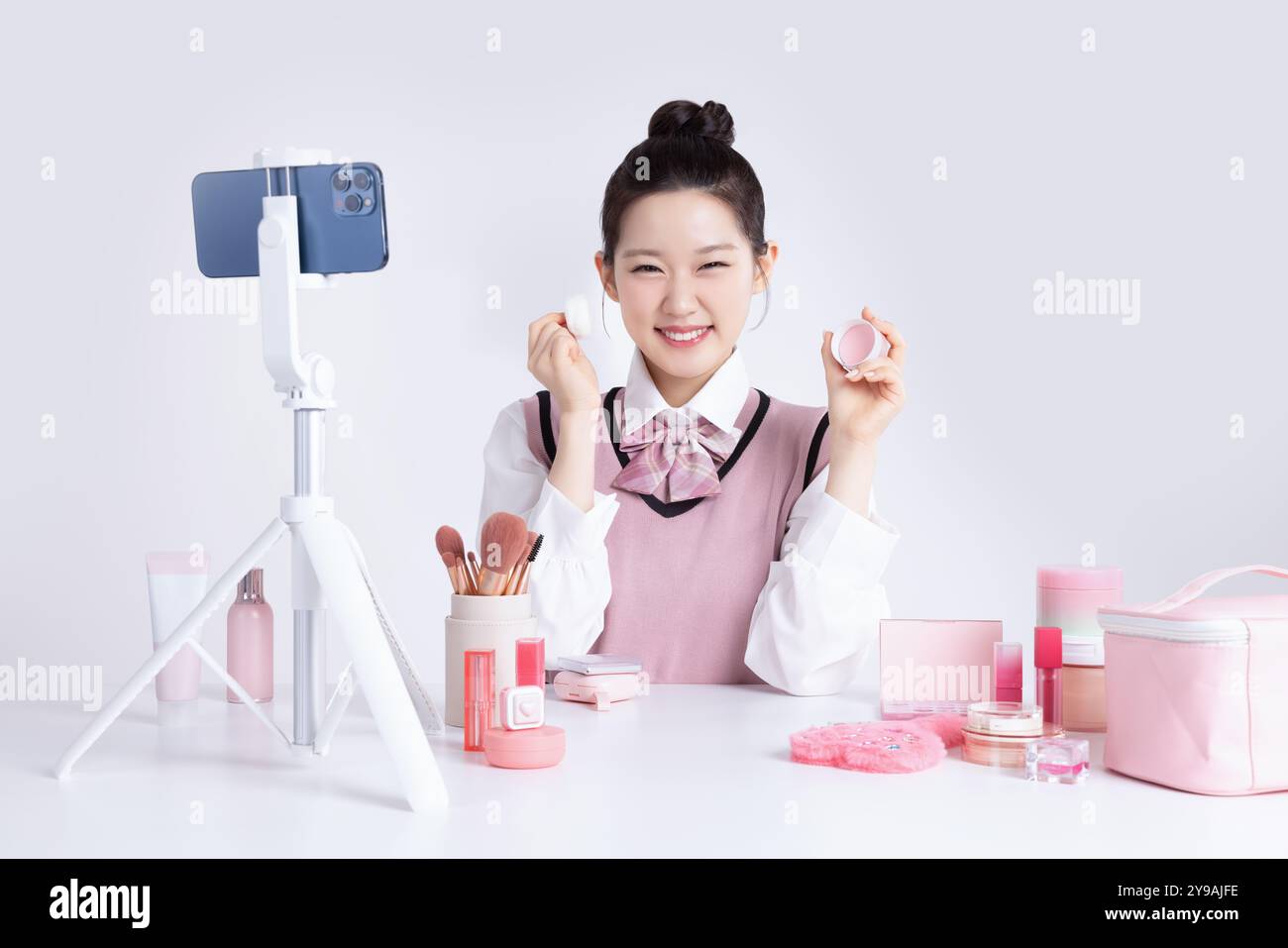 A teenage woman in school uniform laying out various cosmetics and ...