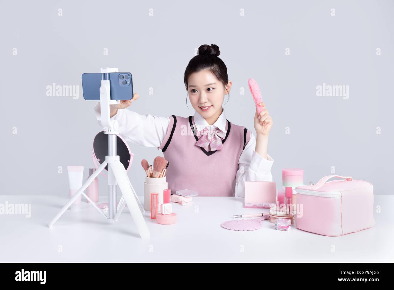 A teenage woman in school uniform laying out various cosmetics and ...