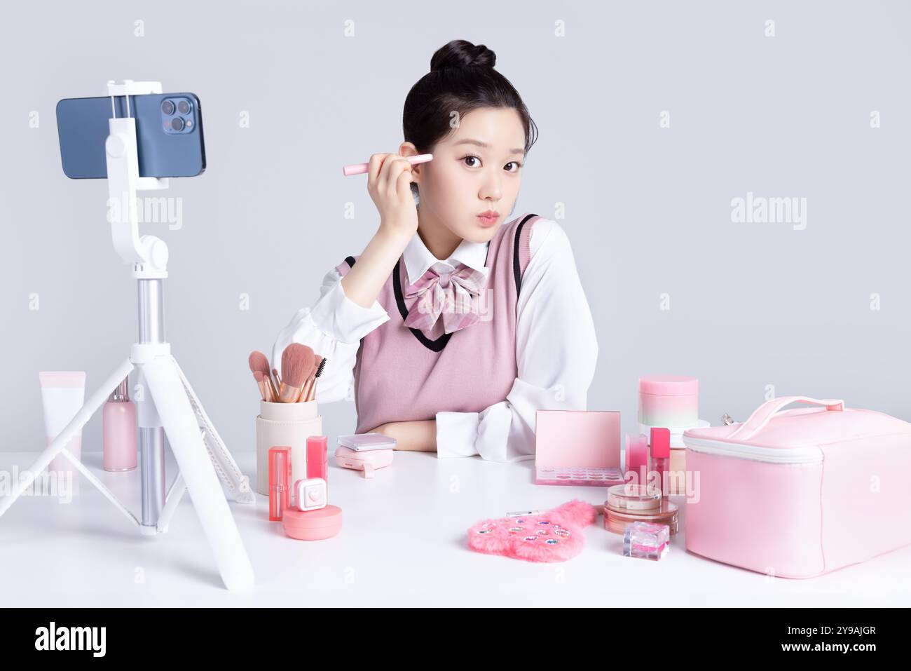 A teenage woman in school uniform laying out various cosmetics and ...