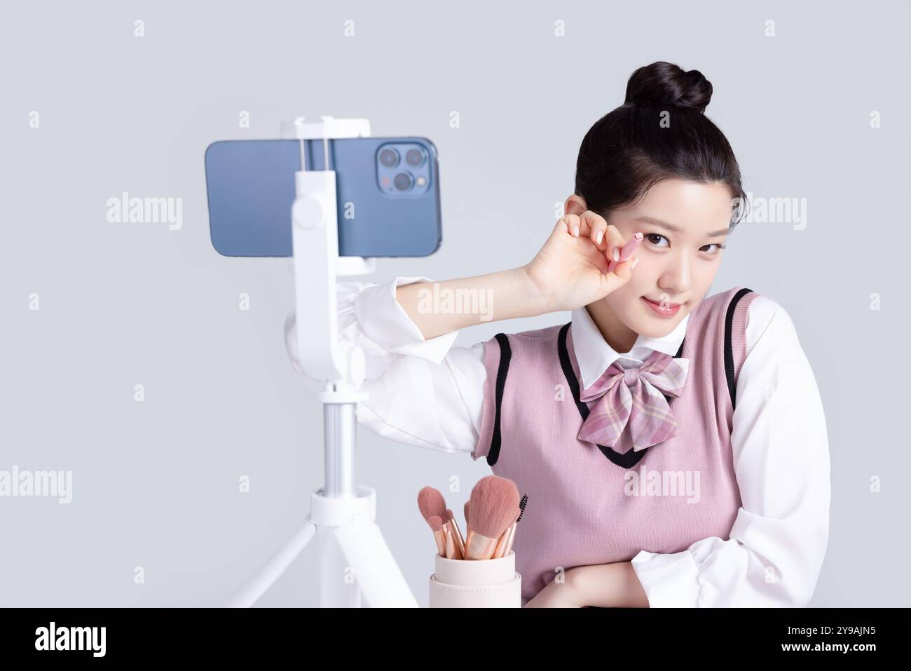 A teenage woman in school uniform laying out various cosmetics and ...