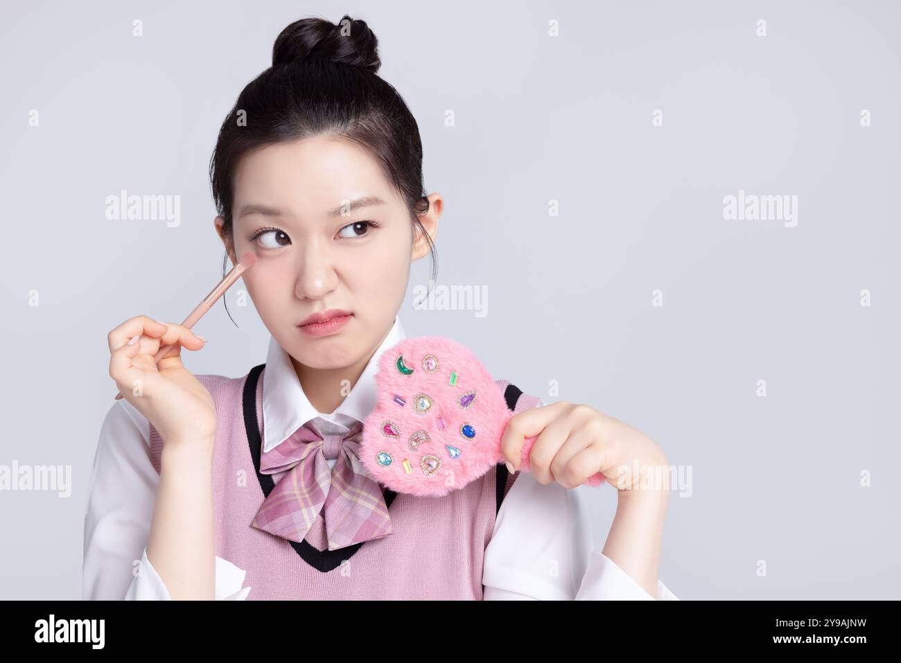 A teenage woman in school uniform laying out various cosmetics and ...