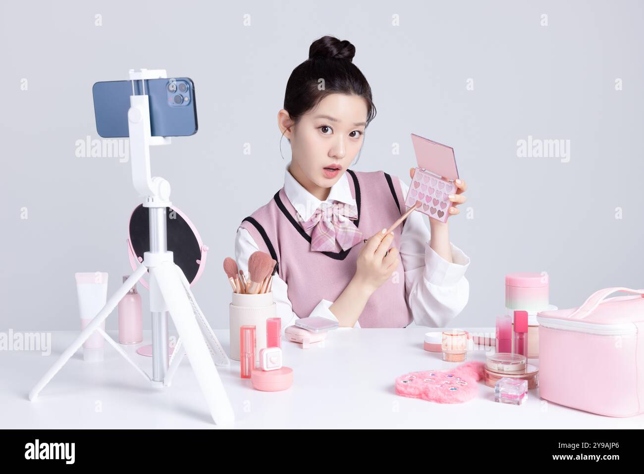 A teenage woman in school uniform laying out various cosmetics and ...