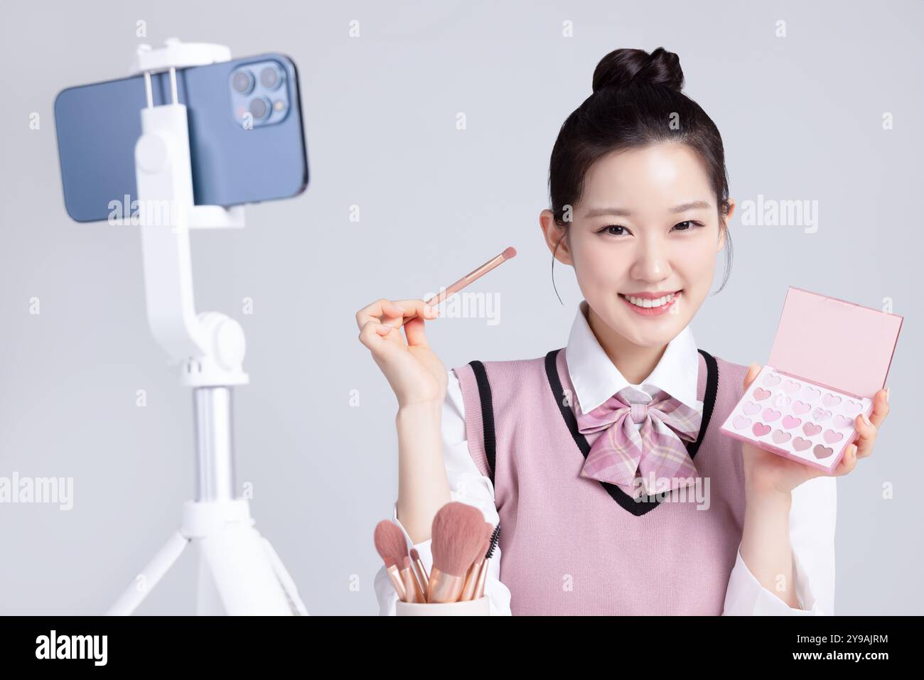 A teenage woman in school uniform laying out various cosmetics and ...