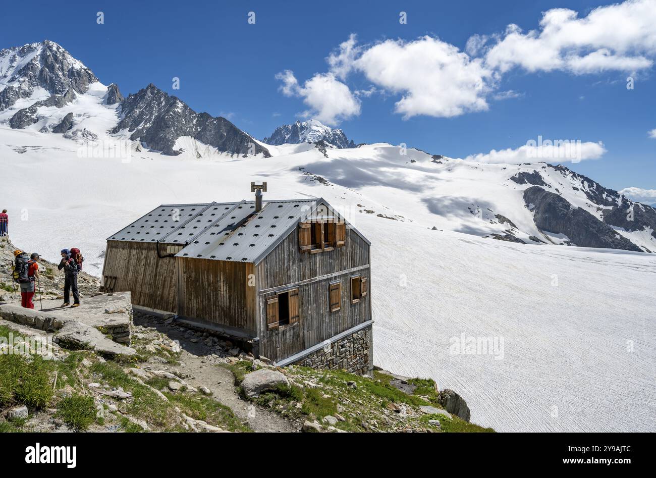 Mountaineer next to a mountain hut in front of a mountain landscape ...