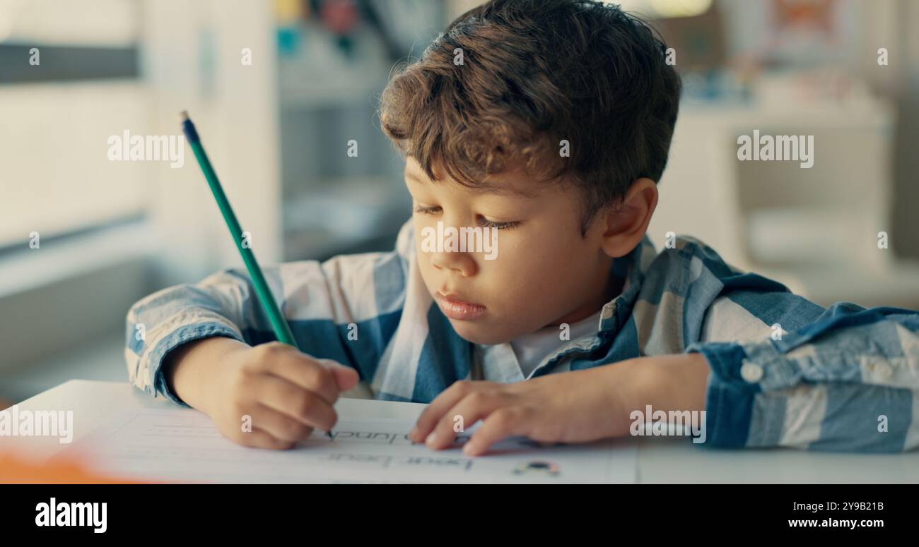Boy, child and writing with paper in classroom for education, learning ...