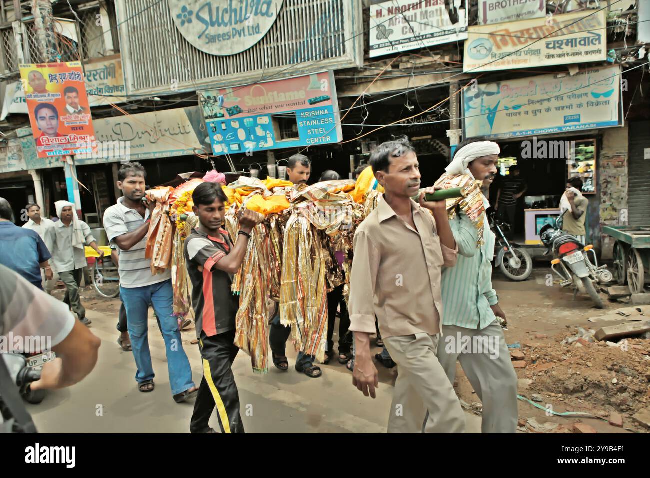 Men carry a body as they are walking on a busy road, heading to one of ...