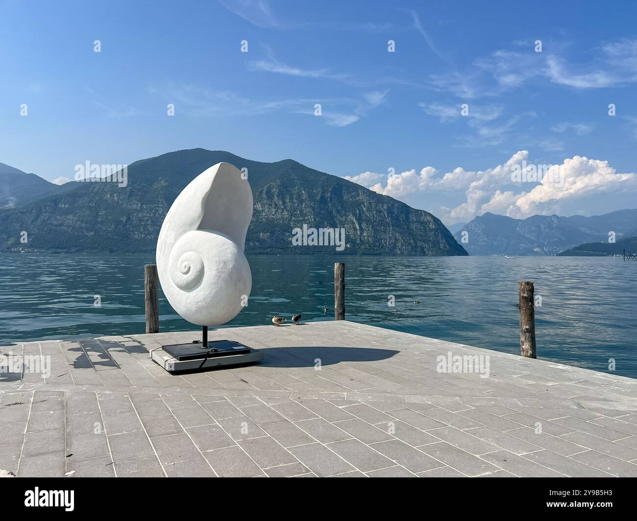 Abstract White Snail Shell Sculpture on a Stone Dock by a Calm Lake ...