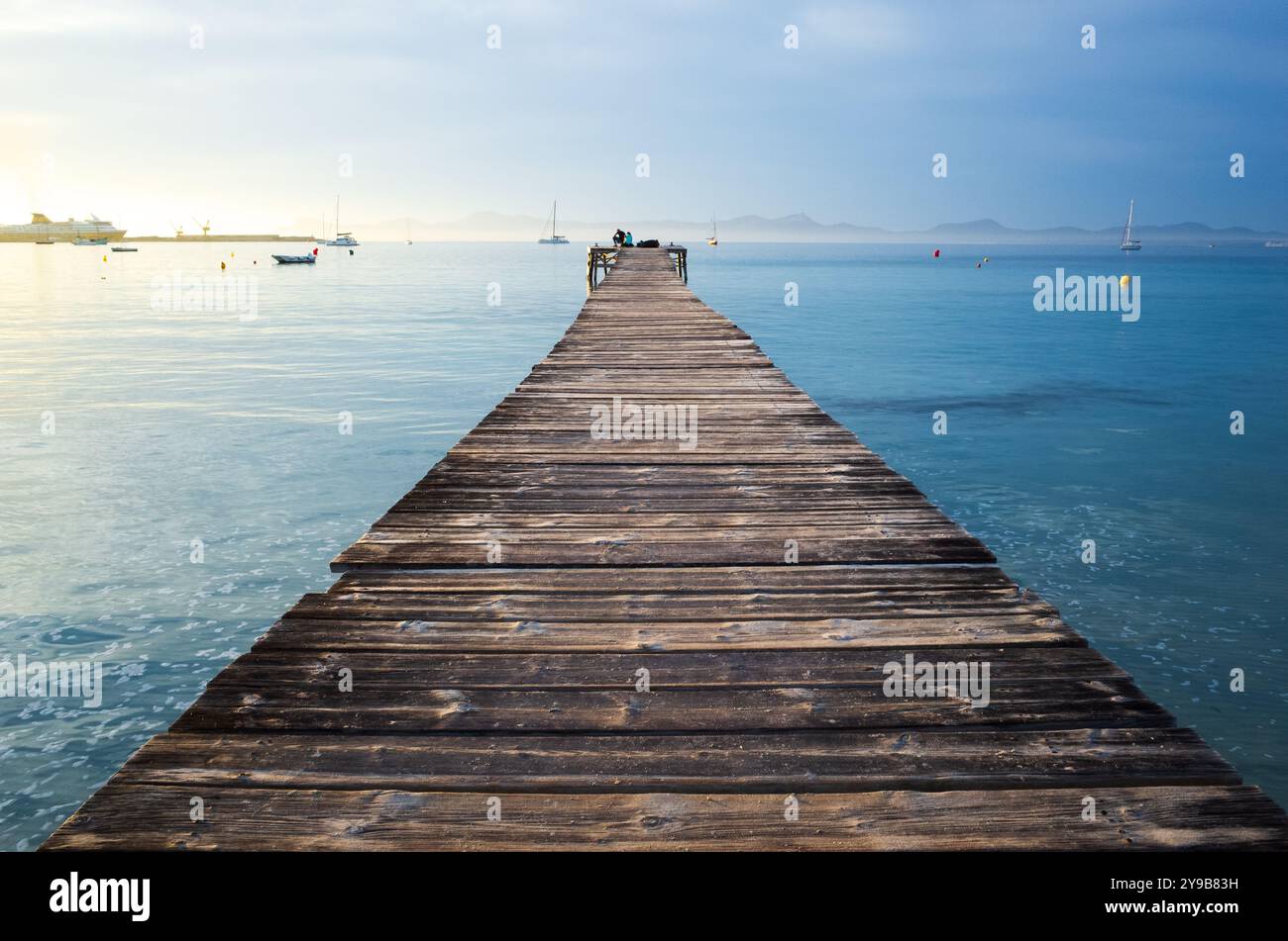 A wooden pier with a view of the ocean. The pier is long and narrow ...