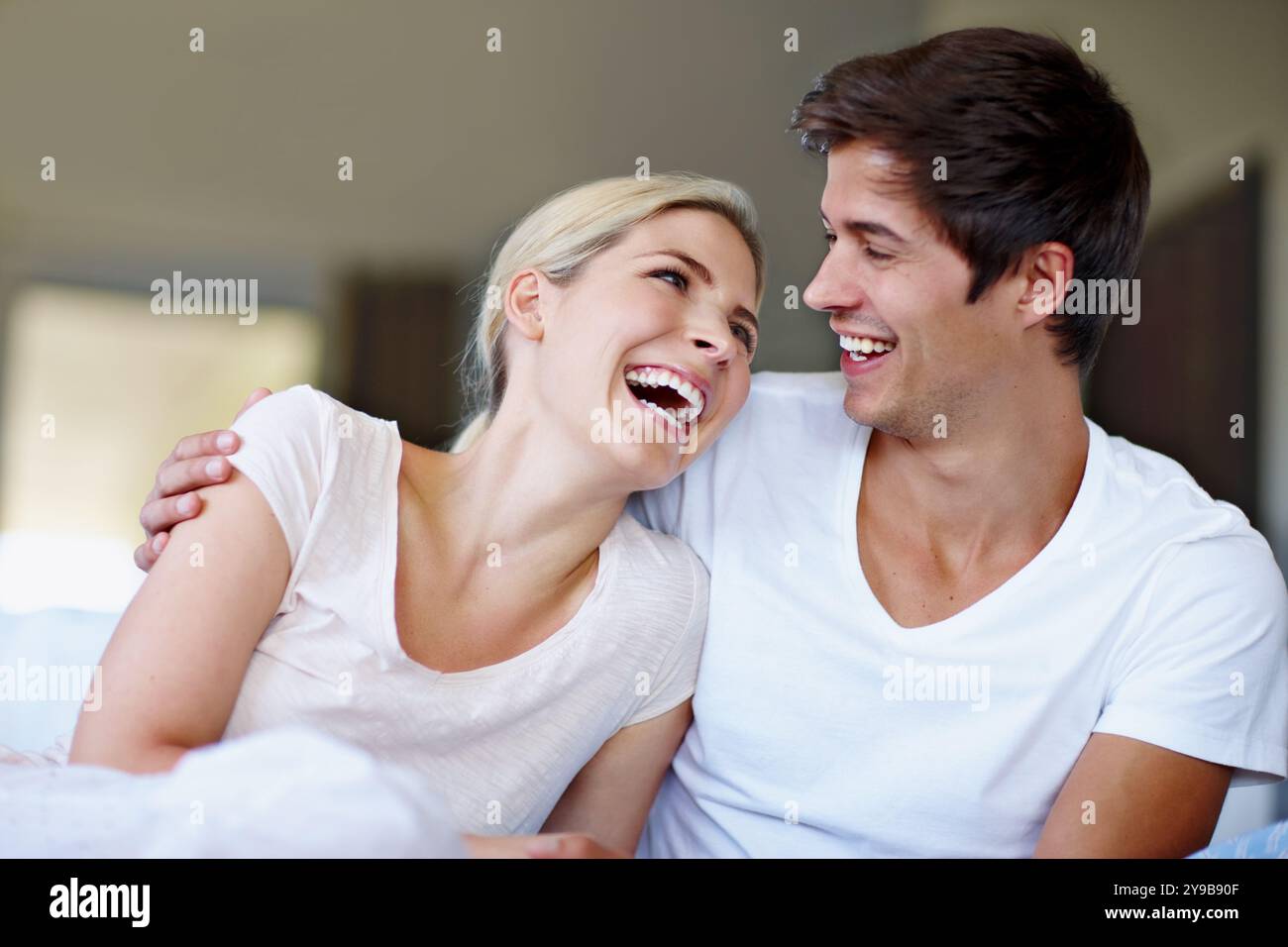 Home, couple and love with laughing for joke, funny memory and bonding ...