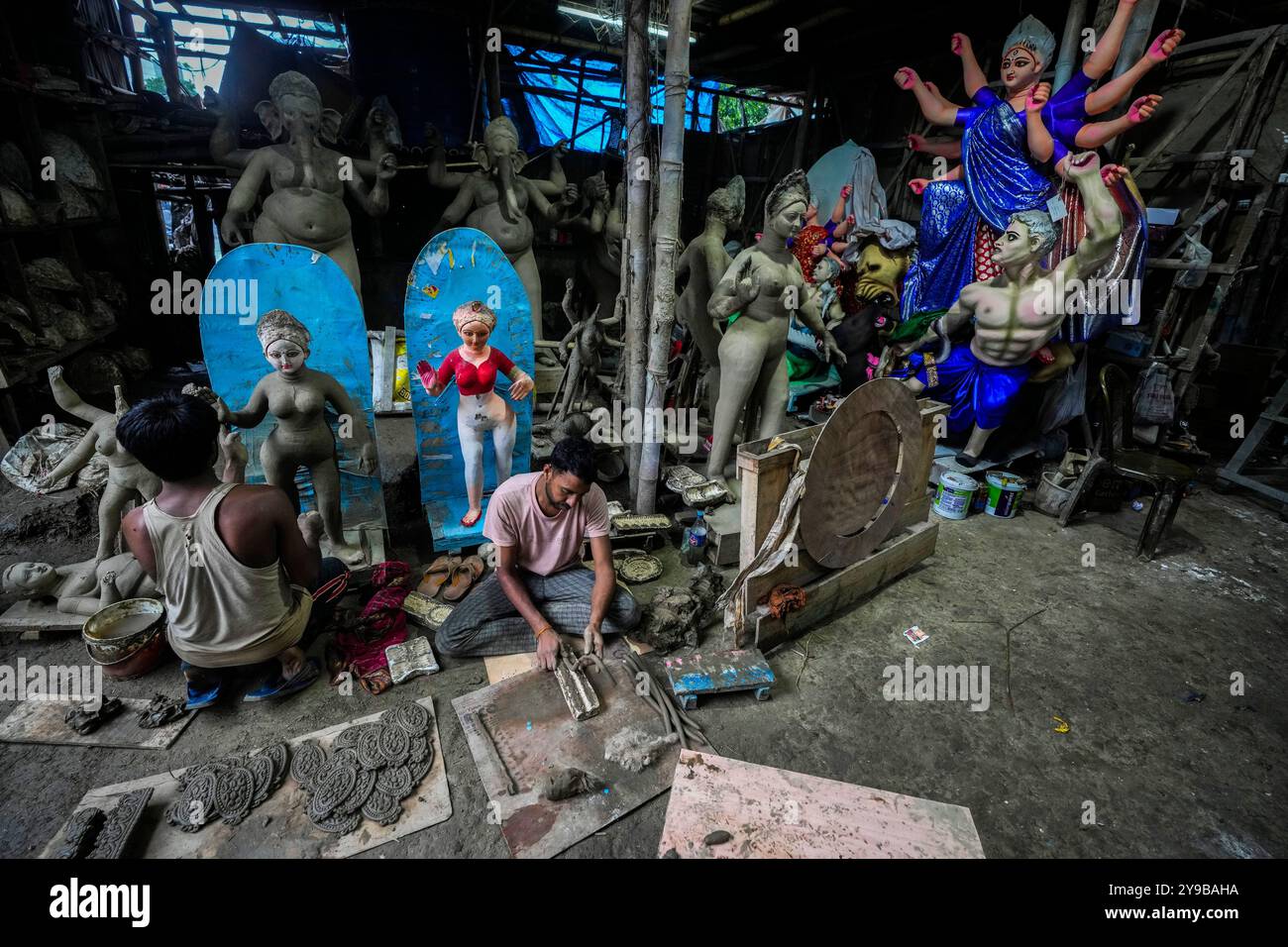 Artisans prepare mud idols of the Hindu goddess Durga and other deities ...