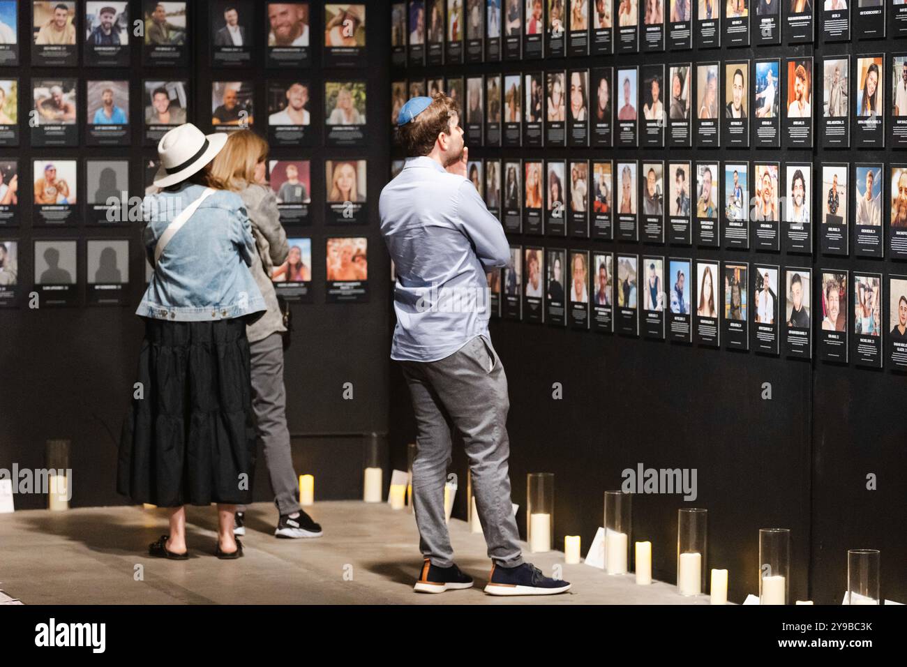 Three people study pictures of victims murdered by Hamas terrorists on ...