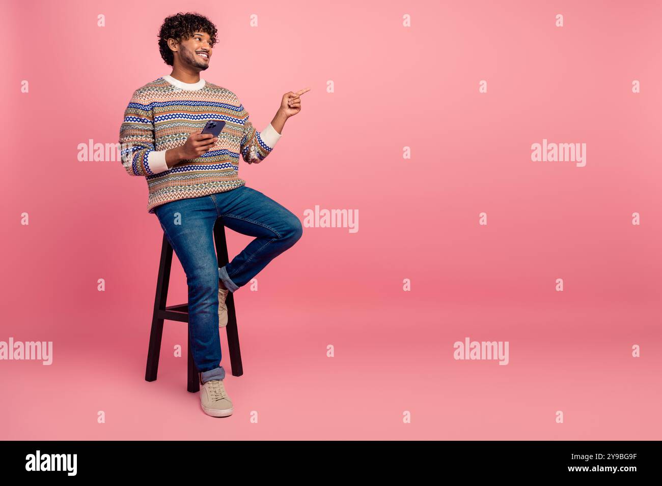 Full size photo of nice young man stool phone direct finger empty space ...