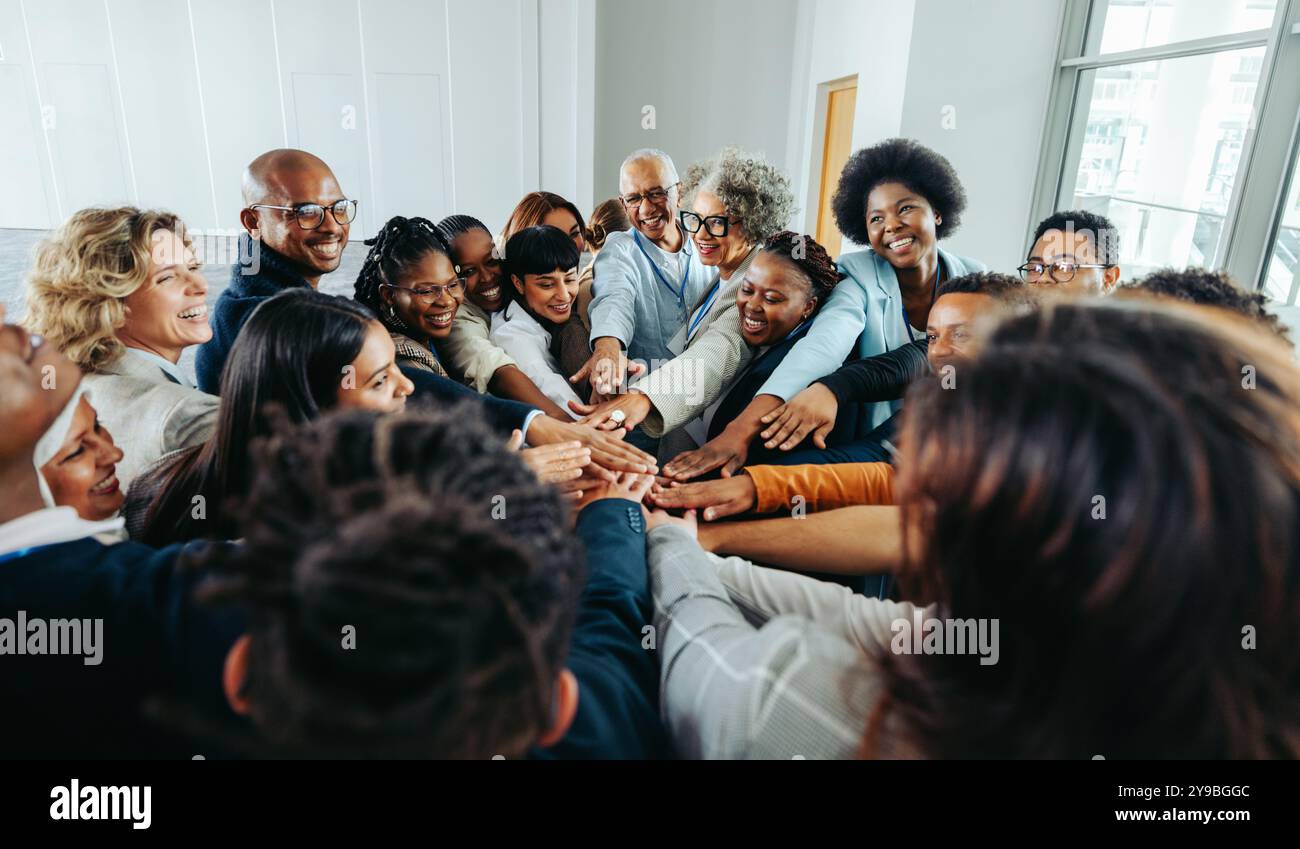 A diverse team of smiling people united in a group huddle, showcasing ...