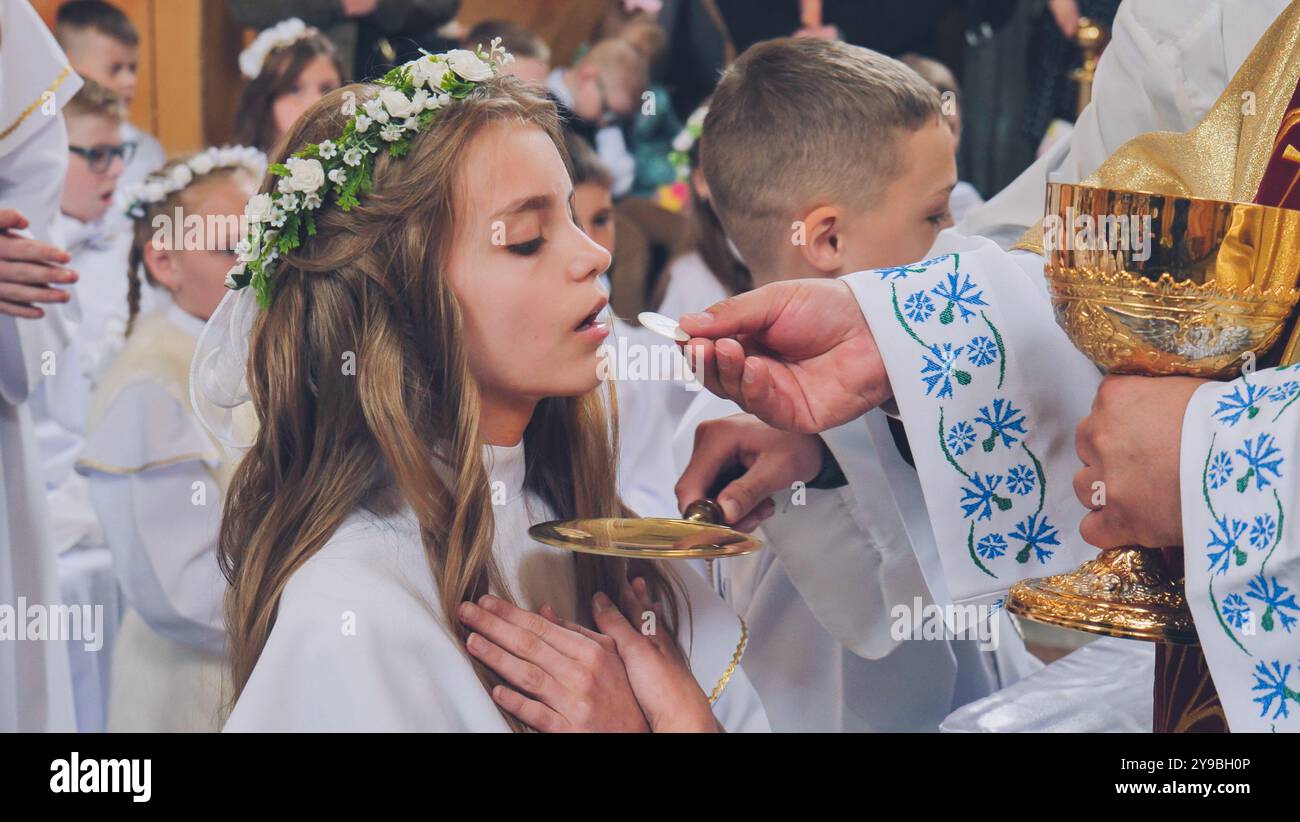 Lida, Belarus - June 15, 2021: Girl receiving first holy communion from ...